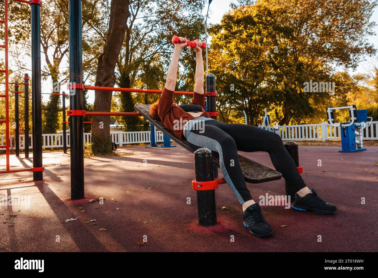 Caucasian mid adult woman does french bench press lies on bench ...