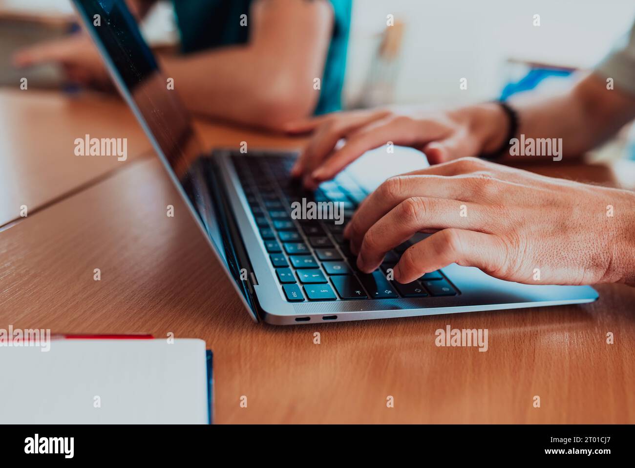 In a close-up view, the fingers of a man are seen typing swiftly on a ...