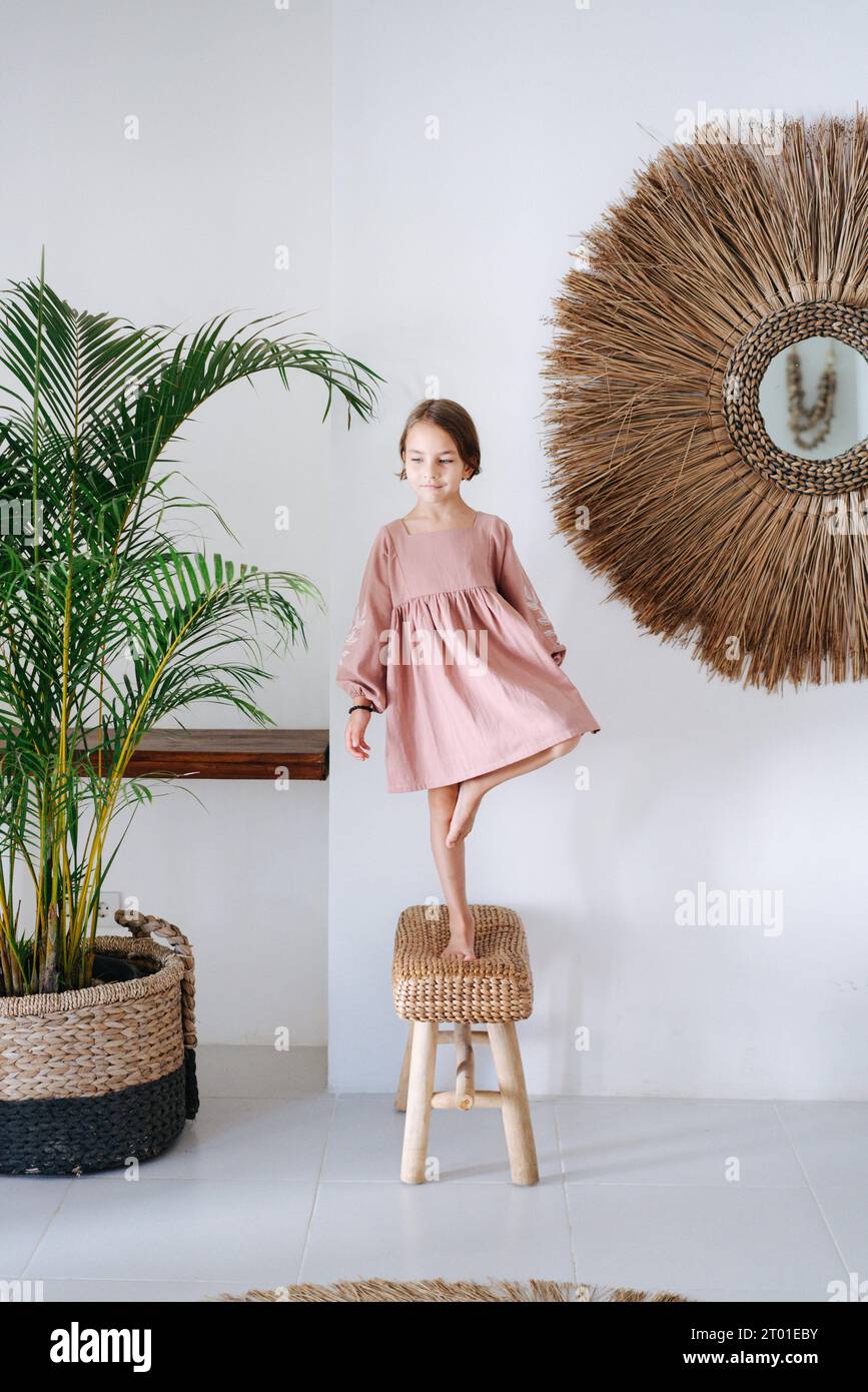 Girl balancing on one leg while standing on a chair Stock Photo - Alamy