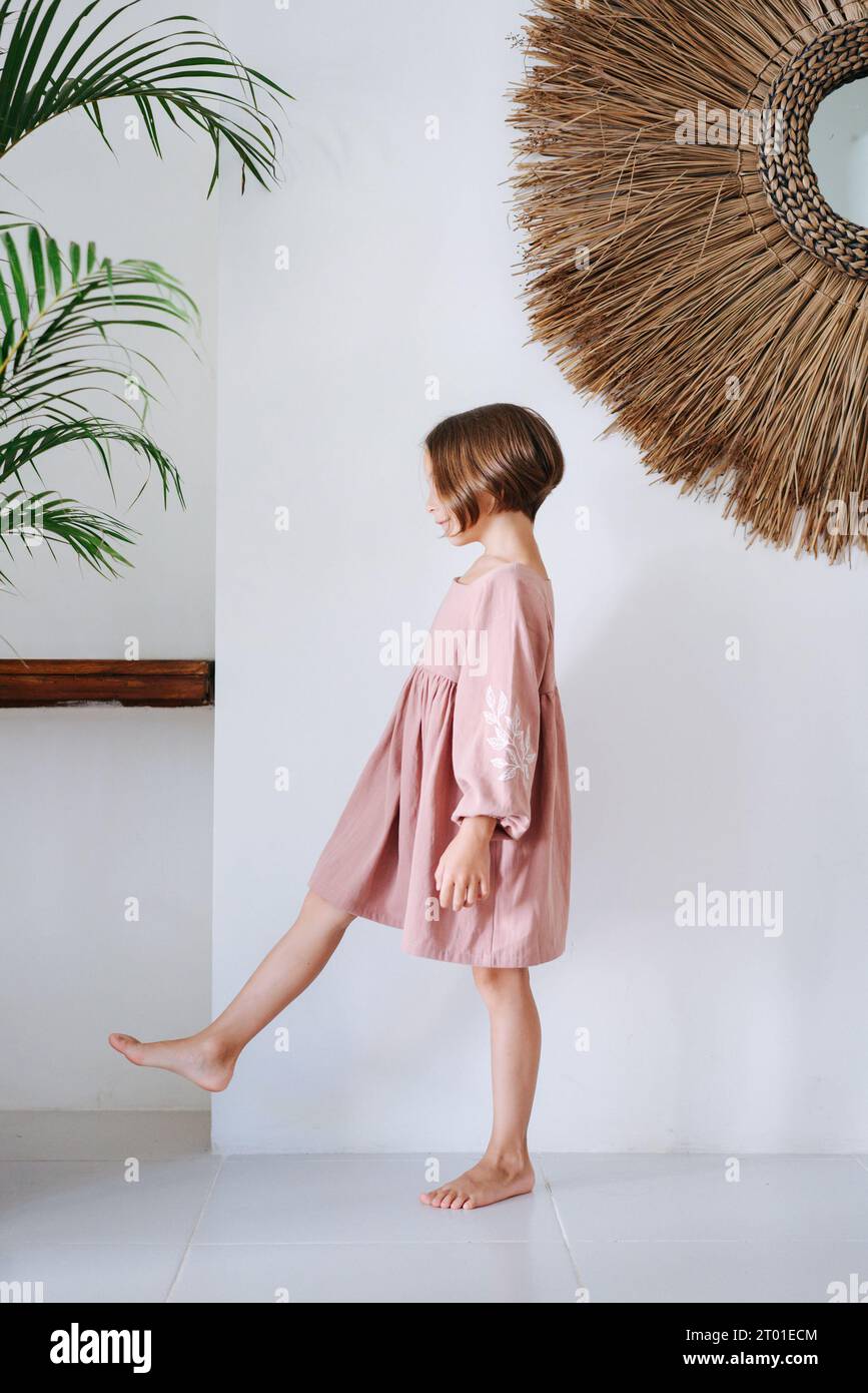Girl in a summer dress raising her leg against a background of a white ...