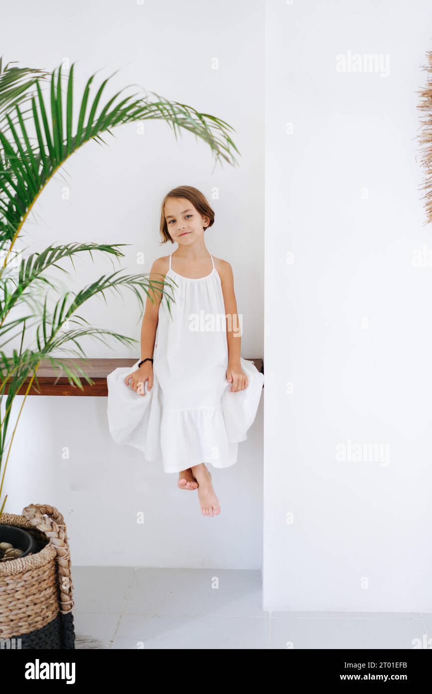 Girl sitting on a shelf in a summer dress, light tropical interior ...