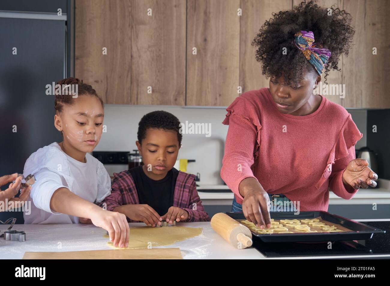 African family cutting cookie shapes in a cookie dough in the kitchen ...
