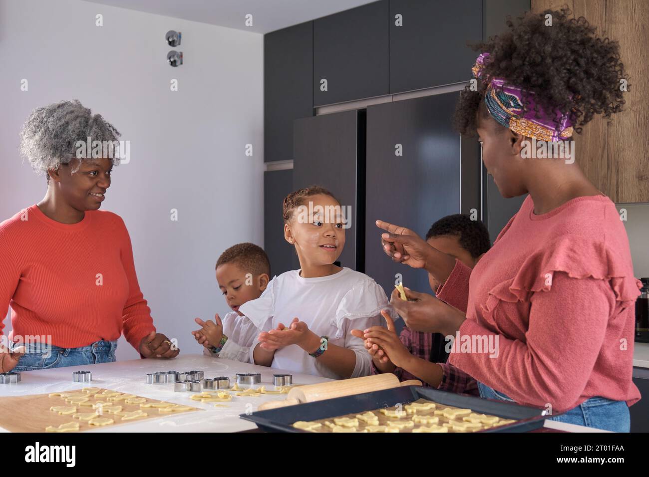African family talking while cutting cookie shapes in a cookie dough in ...