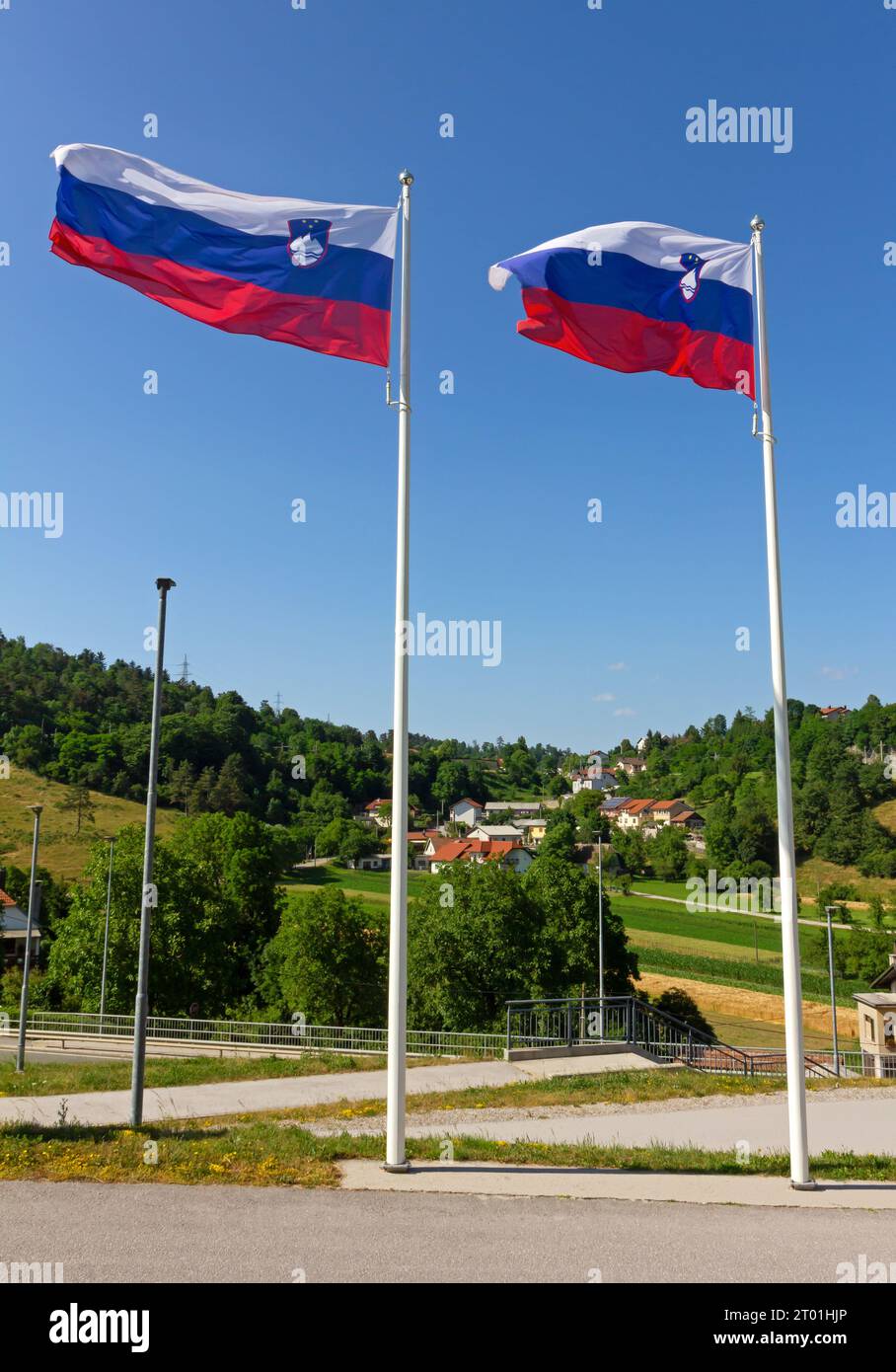 Two waving National flags of Slovenia against a countryside landscape ...