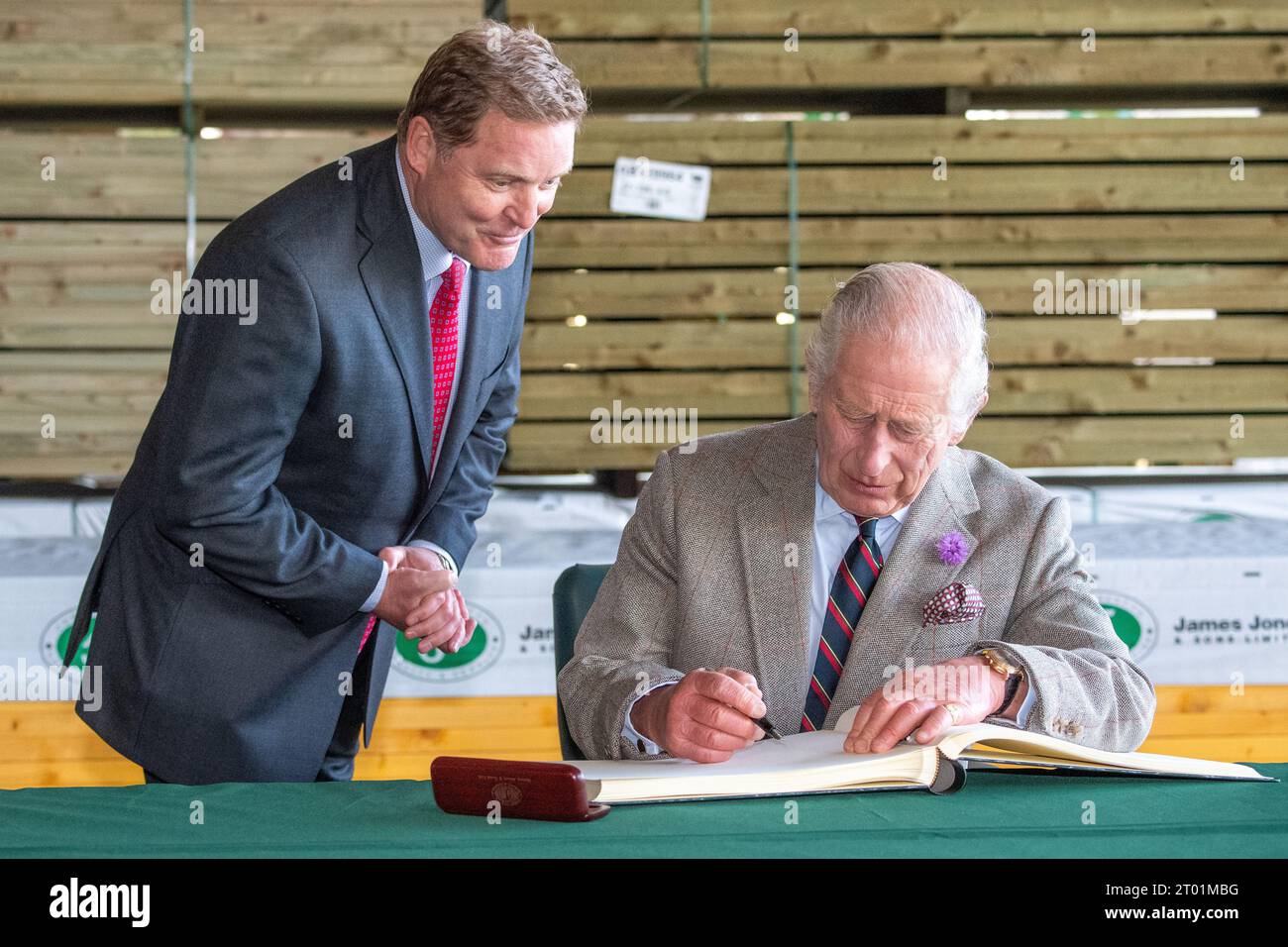 King Charles III signs the visitor book with company chairman Tom Bruce ...