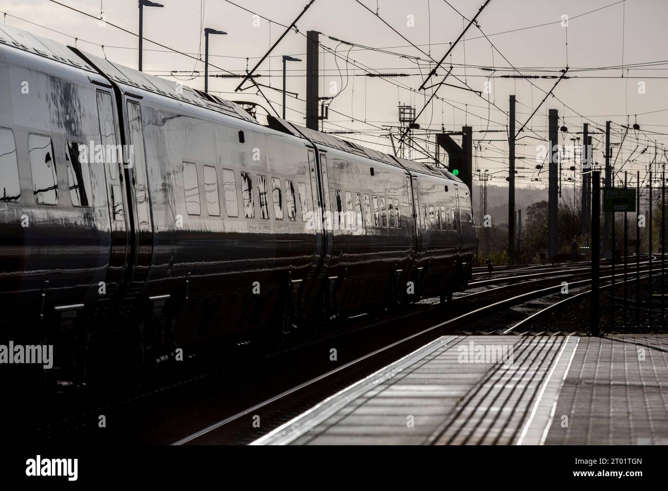 Train at station with overhead electric cables above Stock Photo - Alamy