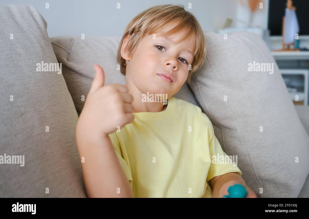 Happy smiling kid showing thumbs up at camera at home.Little boy giving ...