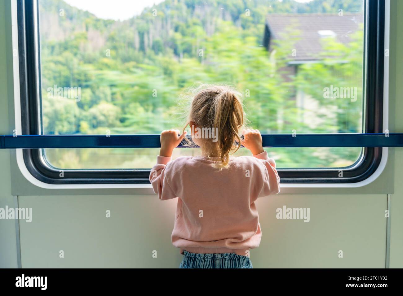 Beautiful little girl looking out train window outside, during moving ...
