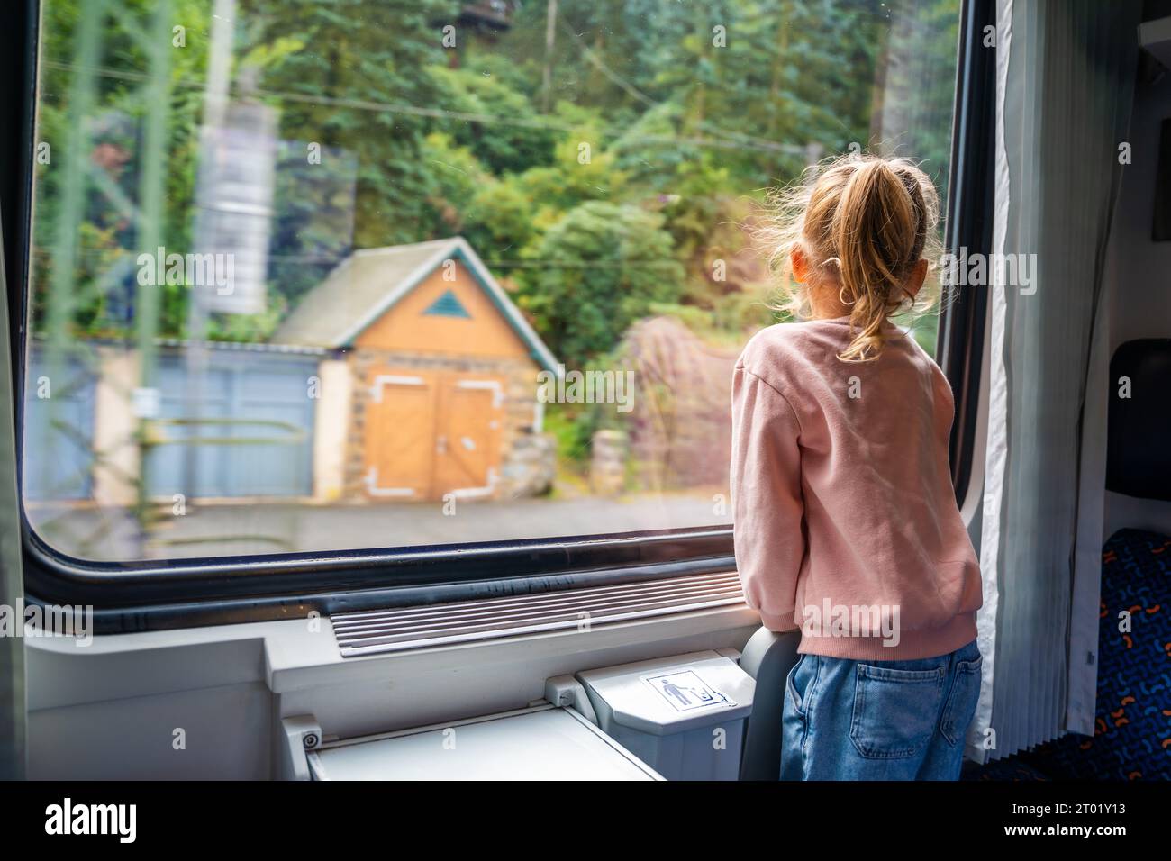 Little girl looking out train window outside, while it moving ...