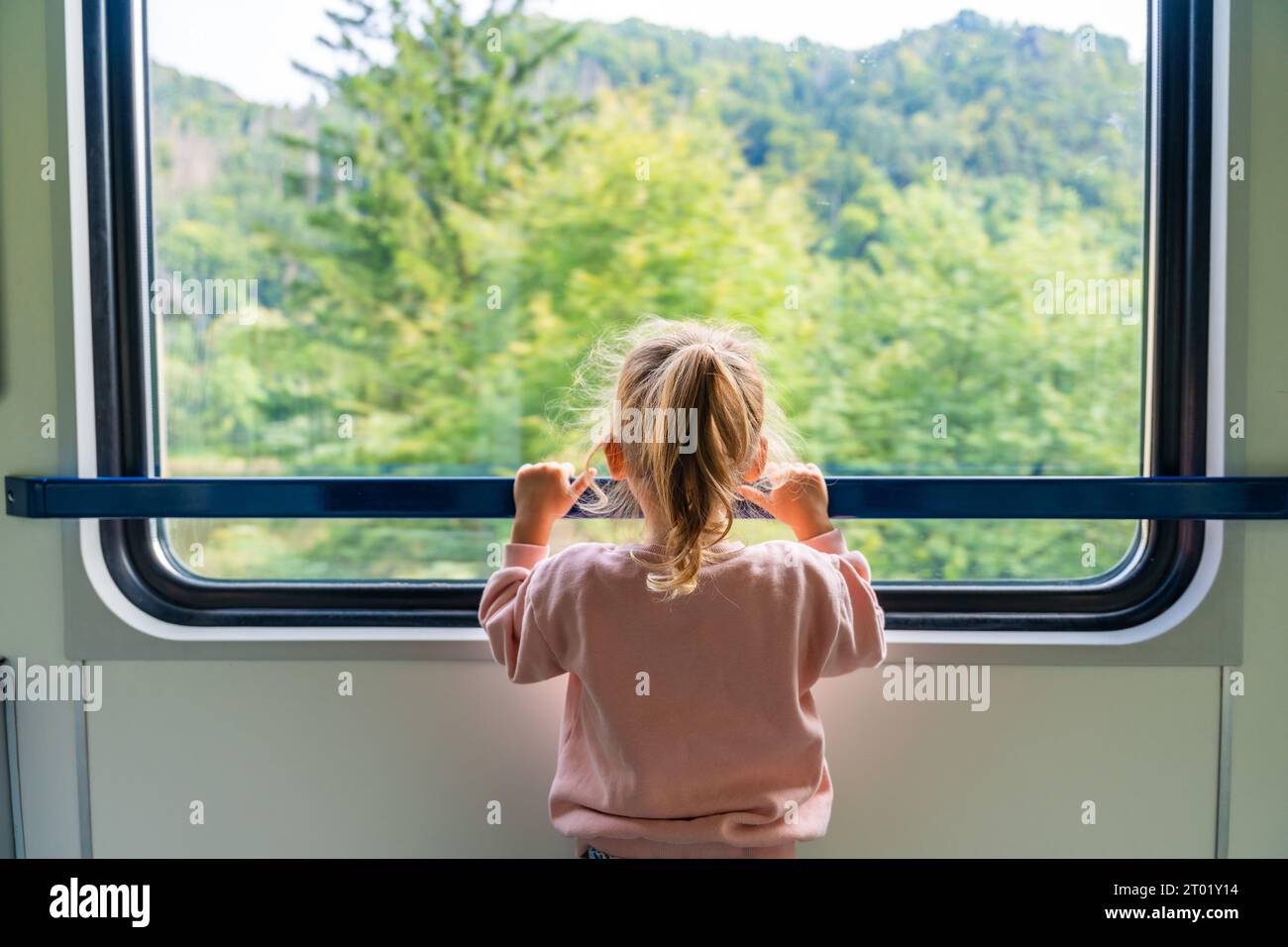 Beautiful little girl looking out train window outside, while it moving ...