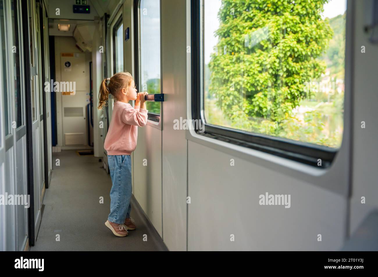 Cute little girl looking out train window outside, while it moving ...