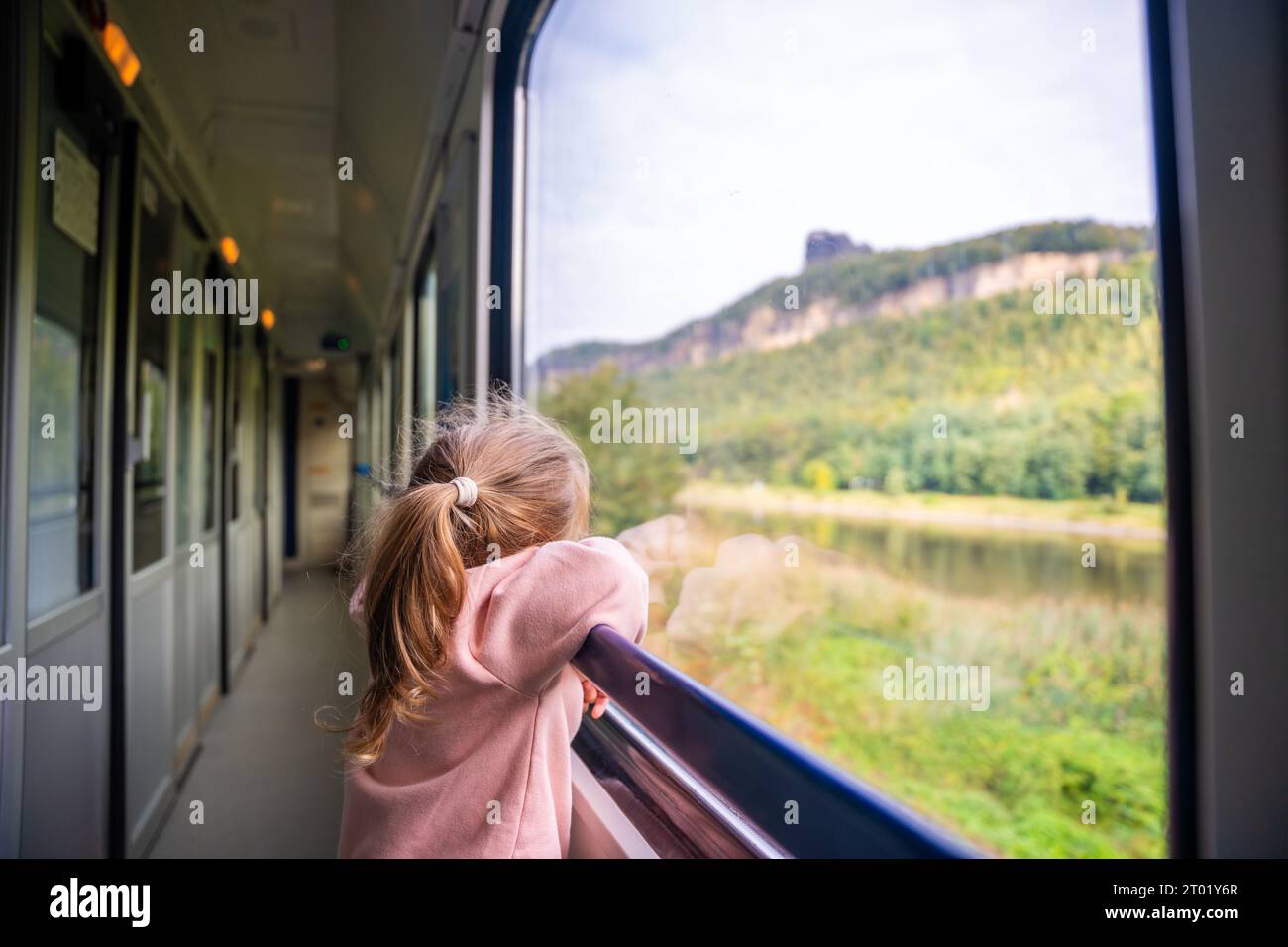 Little girl looking out train window outside, while it moving ...