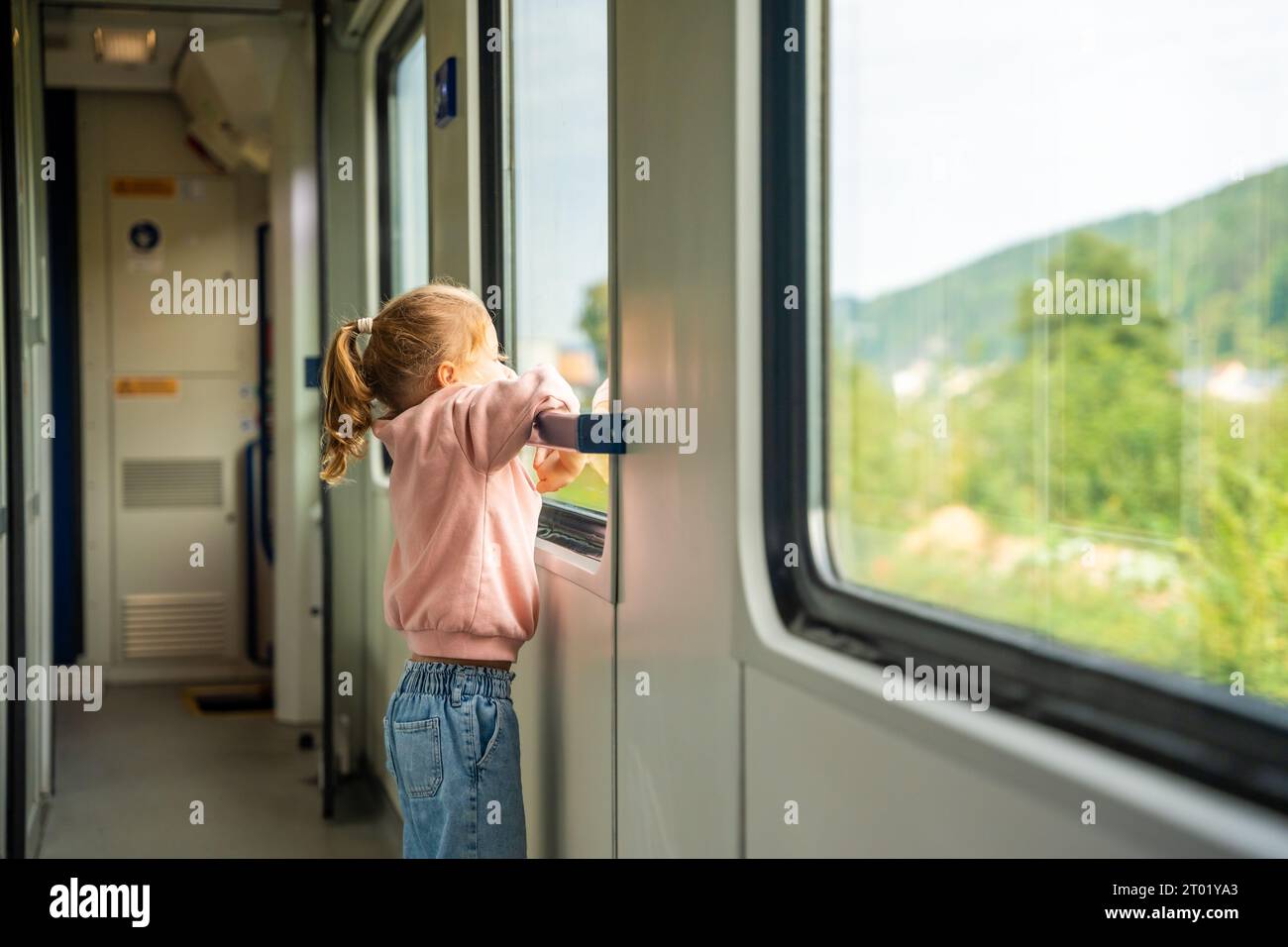 Cute little girl looking out train window outside, while it moving ...