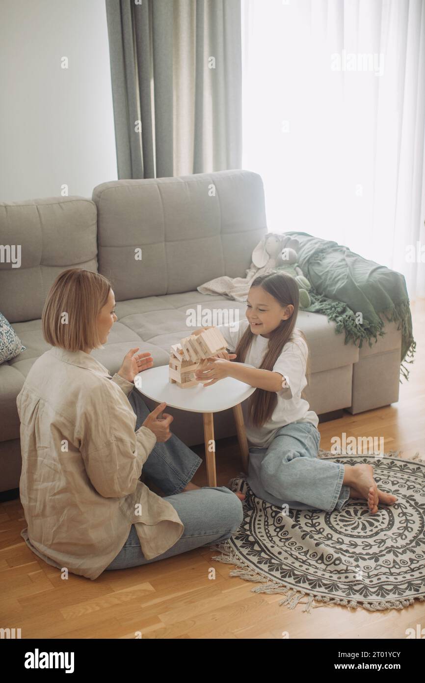 Young woman and her youthful daughter trying to hold on fallen tower ...