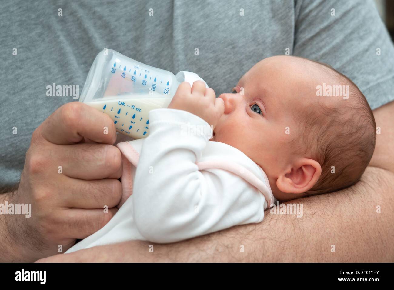 A new father's role, man feeds and holds his baby, offering formula ...