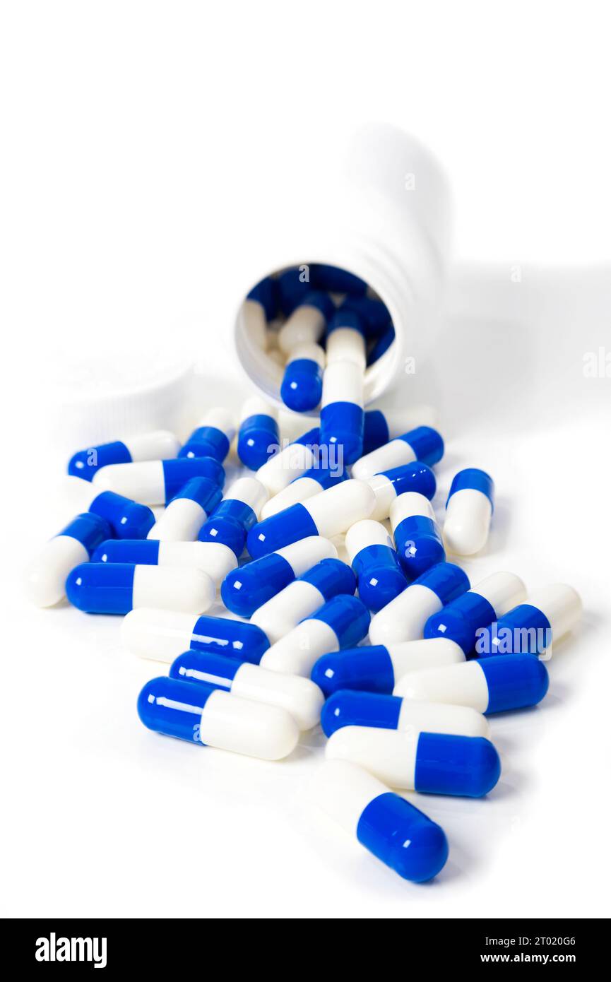 A white pill bottle with blue and white capsules pouring out on a white ...