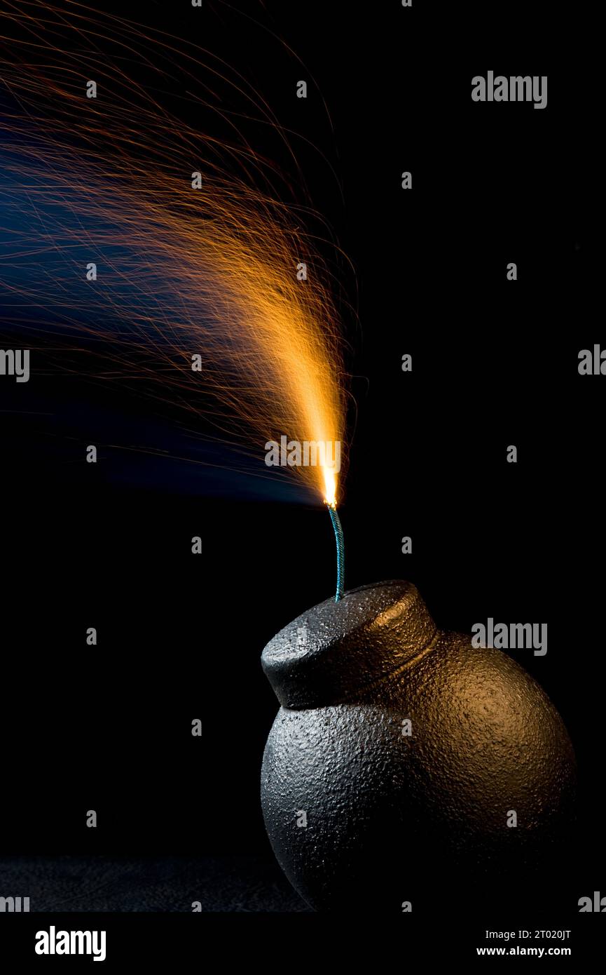 An old round cast iron bomb with lit fuse agaisnt a black background ...