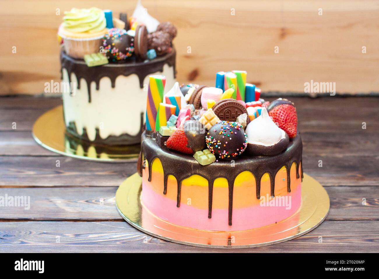 Two bright colorful richly decorated cakes with sweets, popsicles ...
