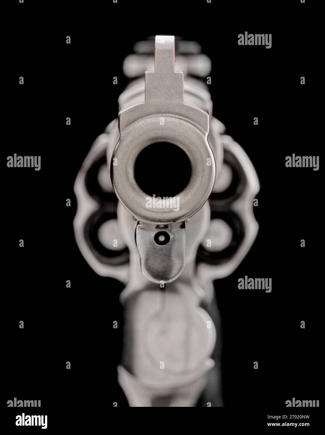 Looking down the barrel of a hand gun barrel against a black background ...
