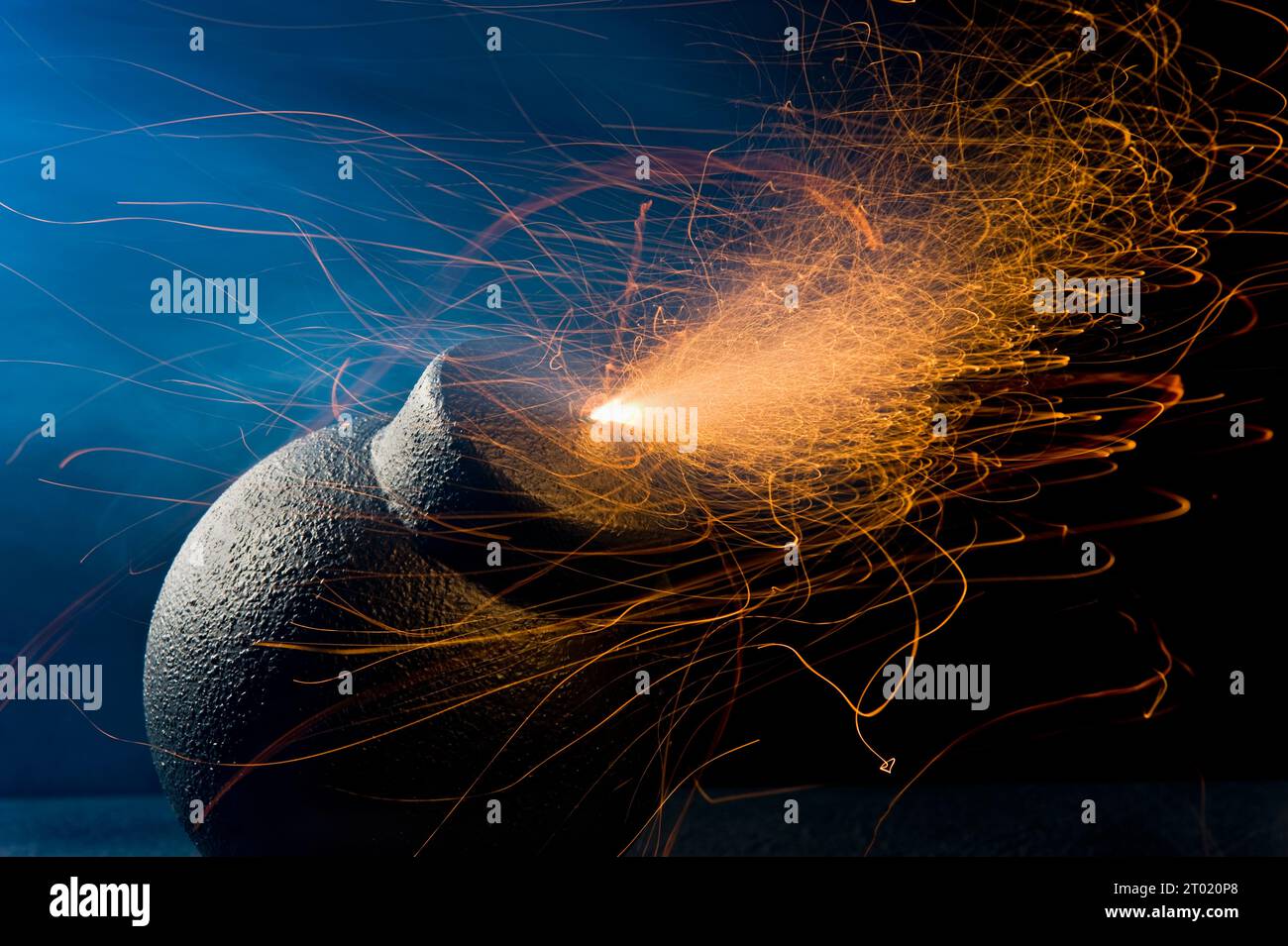 An old round cast iron bomb with lit fuse agaisnt a black background ...