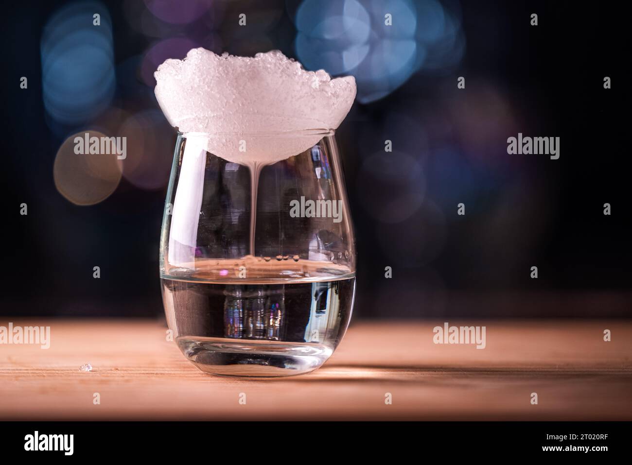 Close up of a clear glass topped with ice with a flaming alcoholic ...