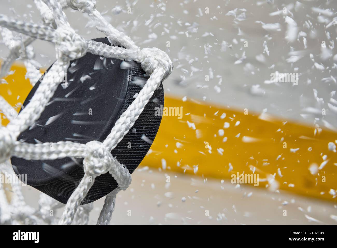 A close-up view of an Ice Hockey puck hitting the back of the goal net ...