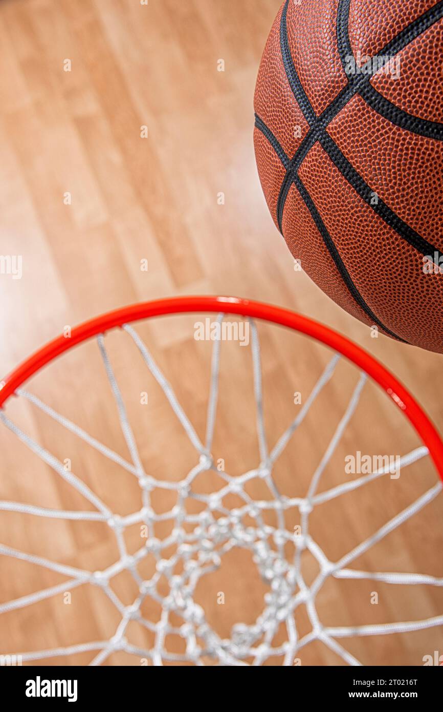 A close-up view looking down at an orange basketball almost going ...