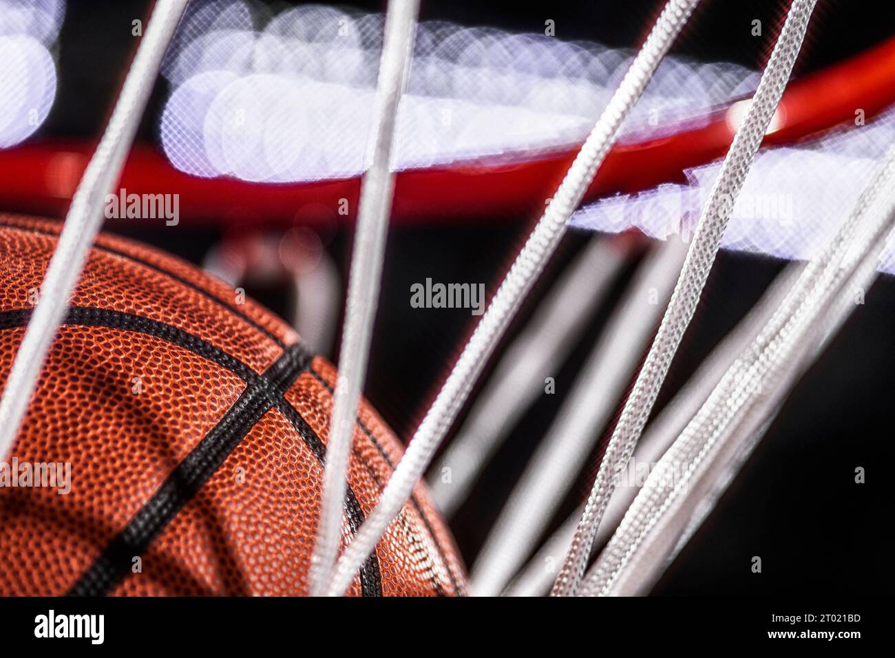 A close-up view at the top of an orange basketball falling through the ...