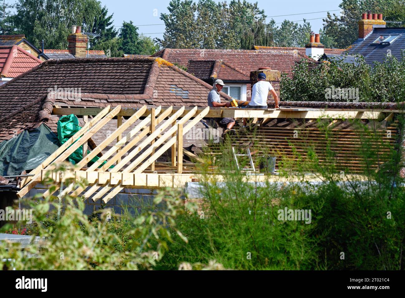 Builders working on a roof extension to a suburban bungalow in ...
