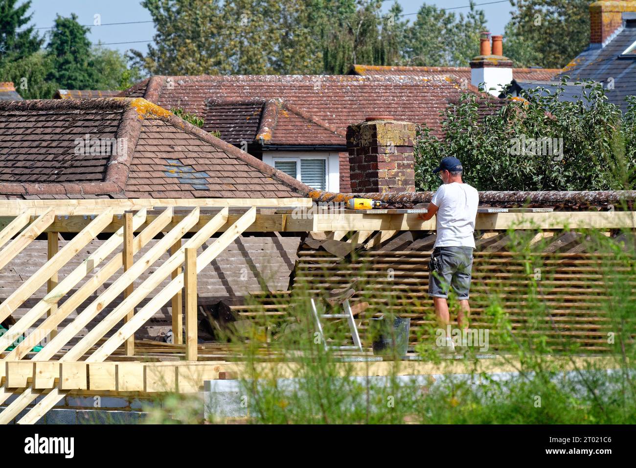 Builders working on a roof extension to a suburban bungalow in ...
