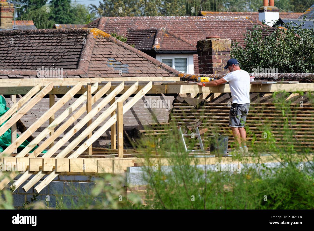 Builders working on a roof extension to a suburban bungalow in ...