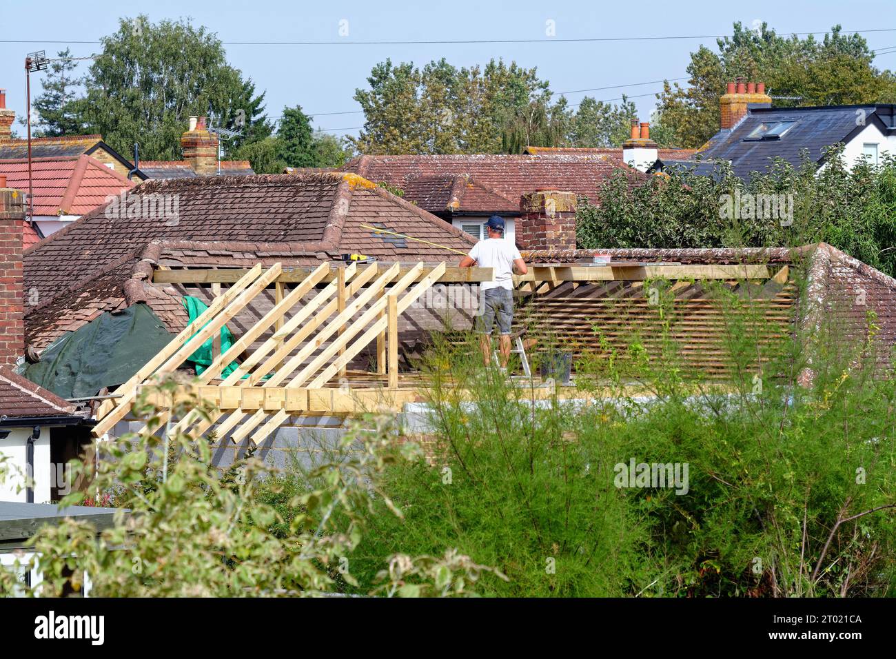 Builders working on a roof extension to a suburban bungalow in ...
