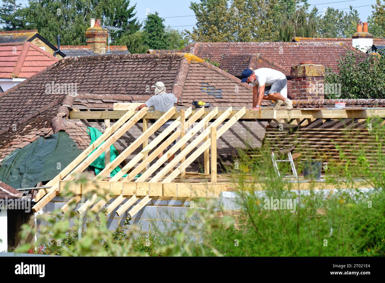 Builders working on a roof extension to a suburban bungalow in ...