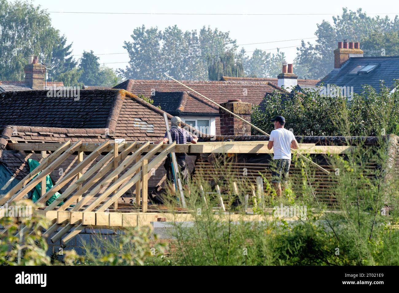Builders working on a roof extension to a suburban bungalow in ...