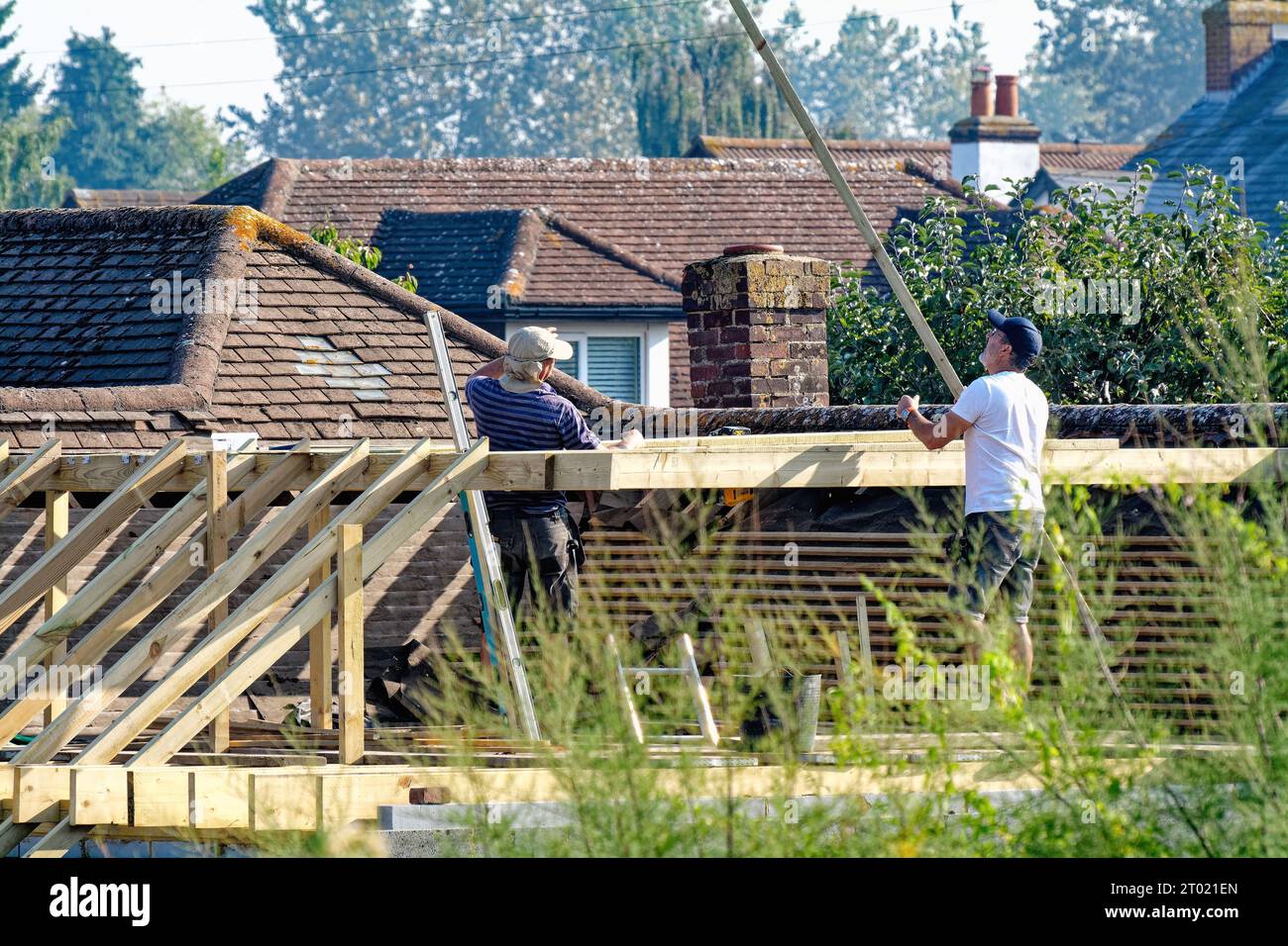 Builders working on a roof extension to a suburban bungalow in ...