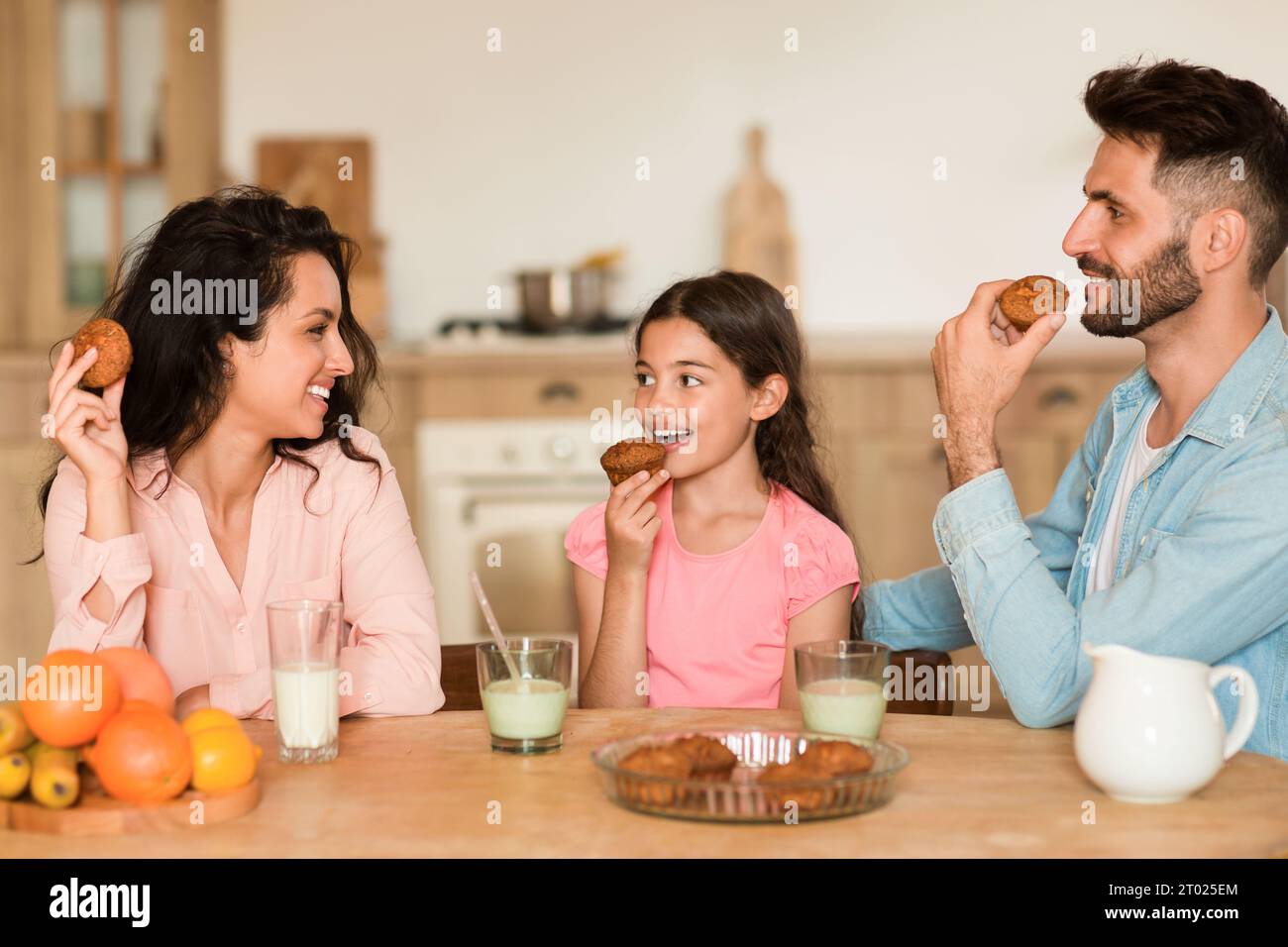 Having a bite. Happy mother, father and their daughter enjoying ...