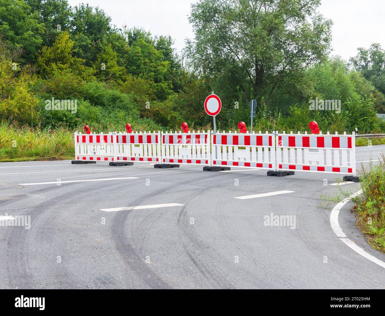 Asphalt road is blocked with a red and white plastic barriers due to ...