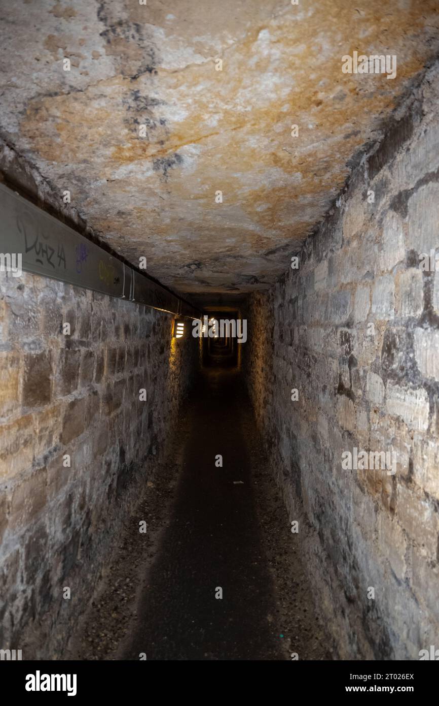 In the Paris Catacombs, a long underground path with structures formed ...