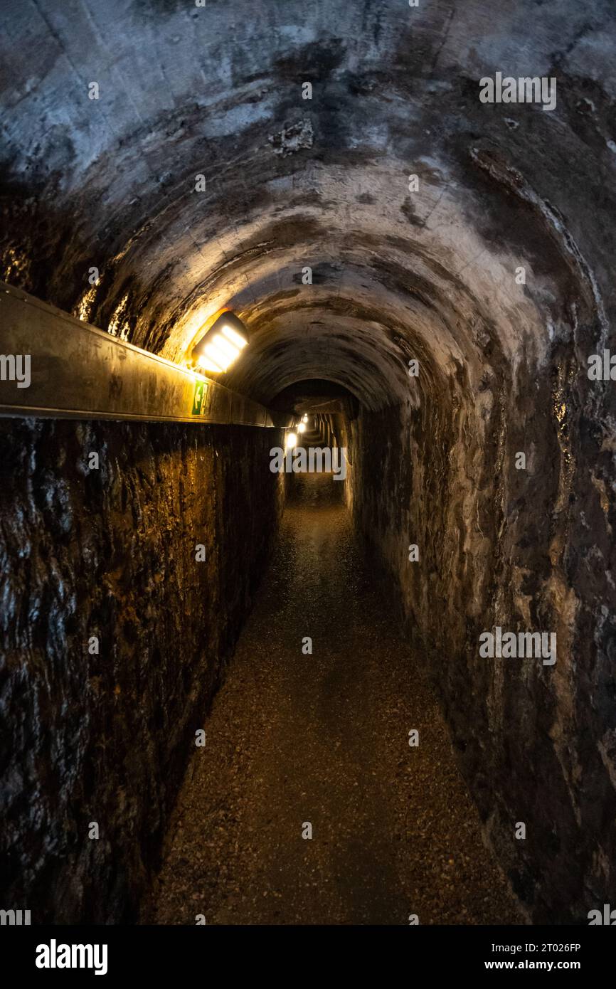 In the Paris Catacombs, a long underground path with structures formed ...