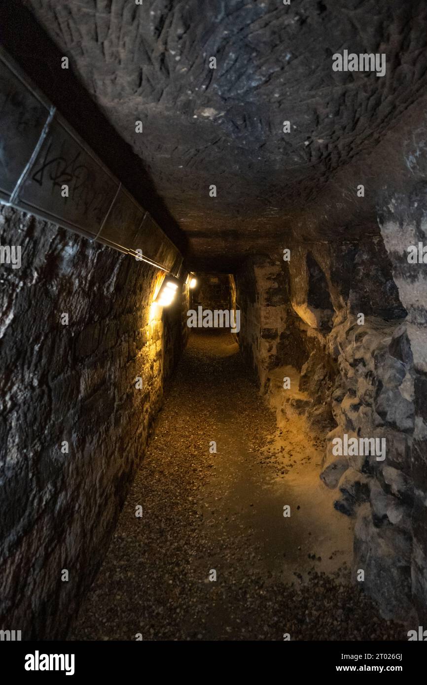 In the Paris Catacombs, a long underground path with structures formed ...
