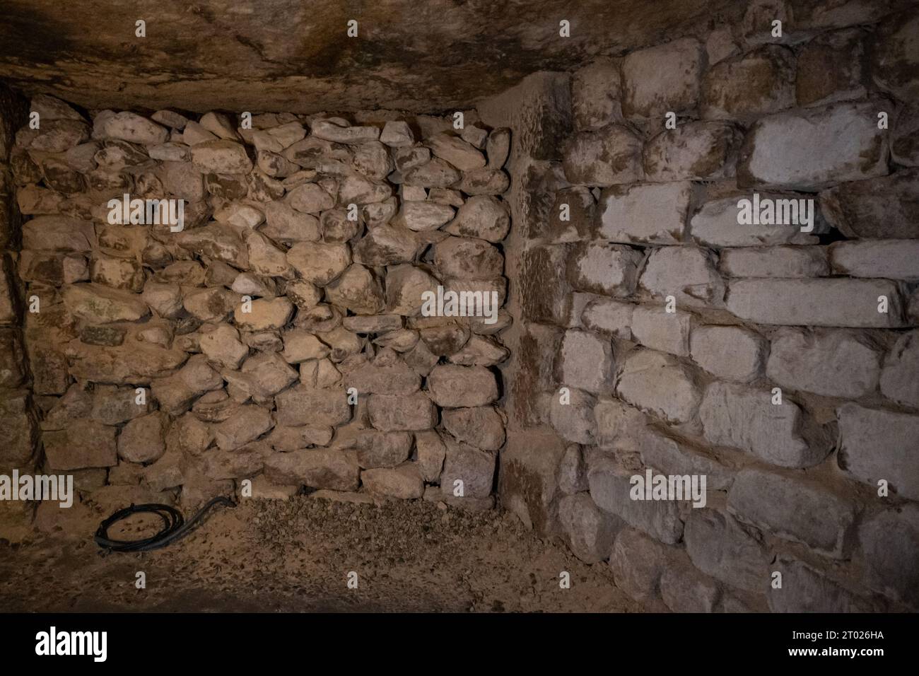 In the Paris Catacombs, a long underground path with structures formed ...