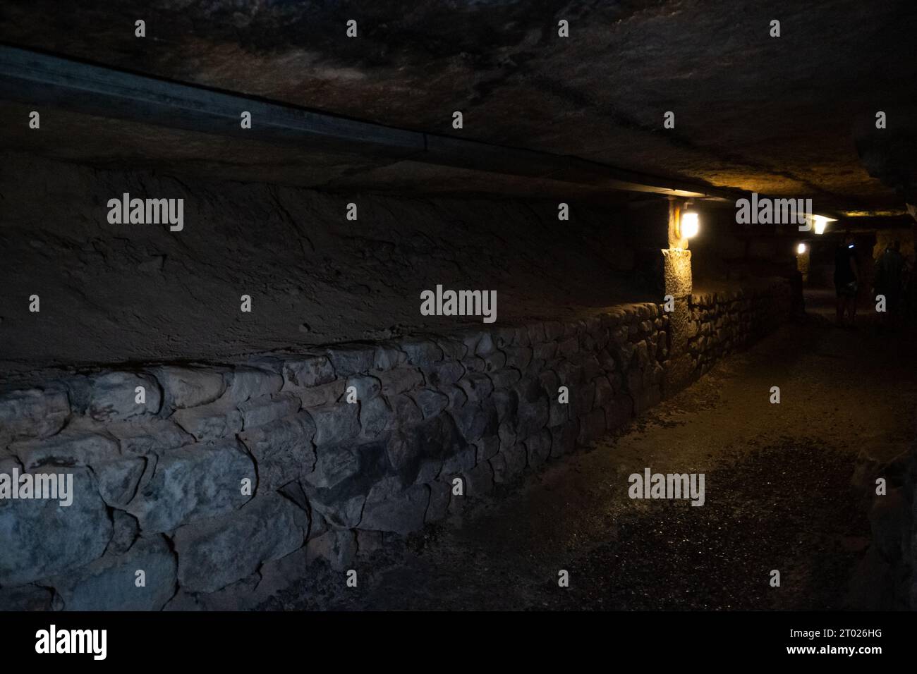 In the Paris Catacombs, a long underground path with structures formed ...