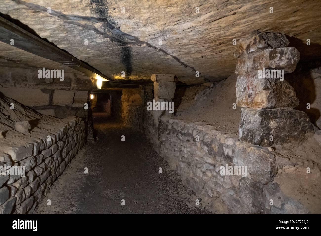 In the Paris Catacombs, a long underground path with structures formed ...