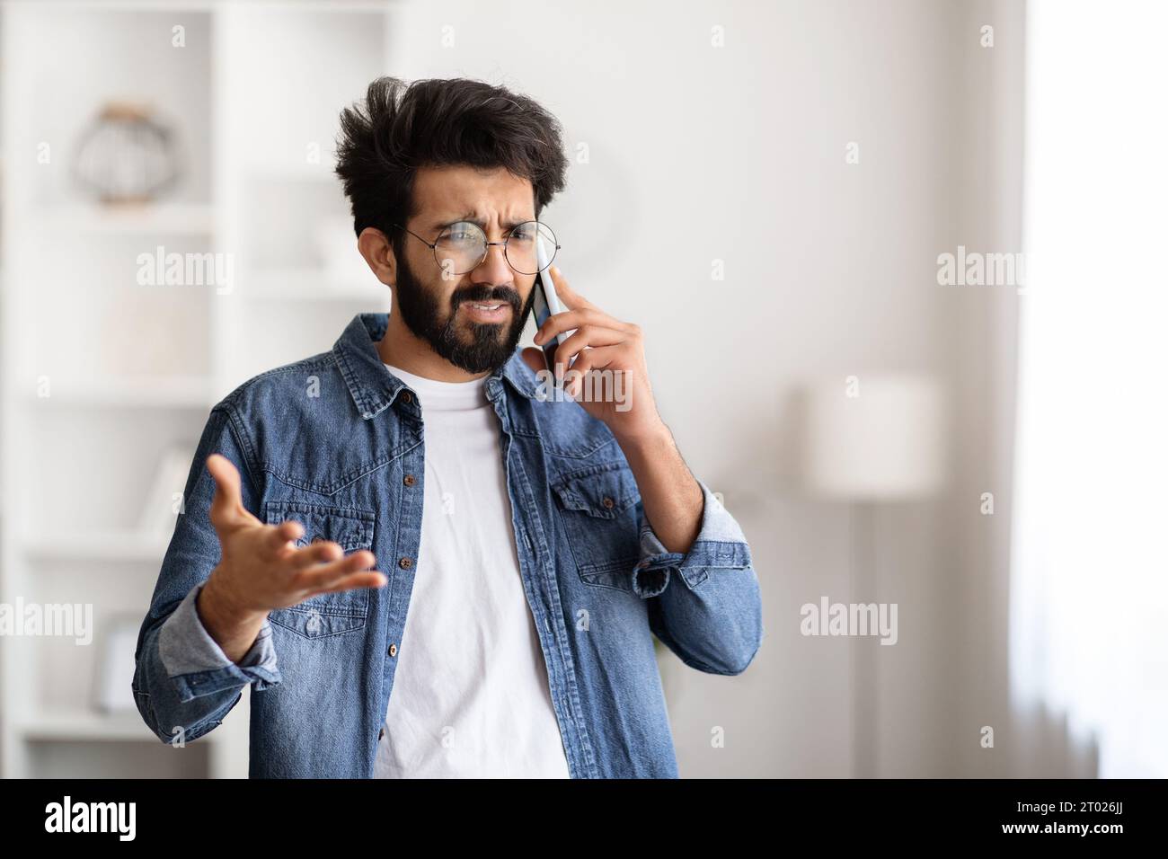 Portrait Of Stressed Young Indian Man Talking On Cellphone At Home ...
