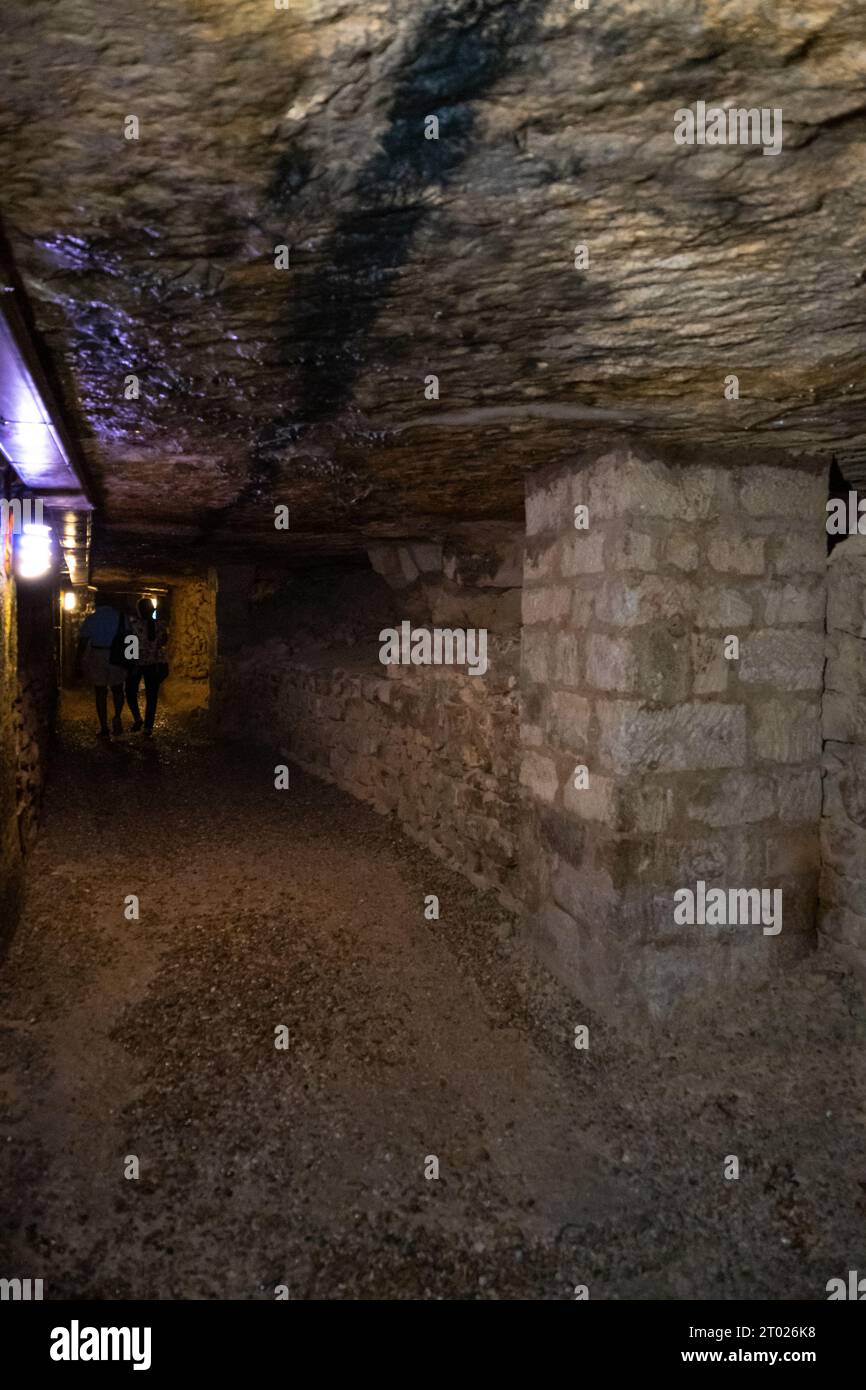 In the Paris Catacombs, a long underground path with structures formed ...