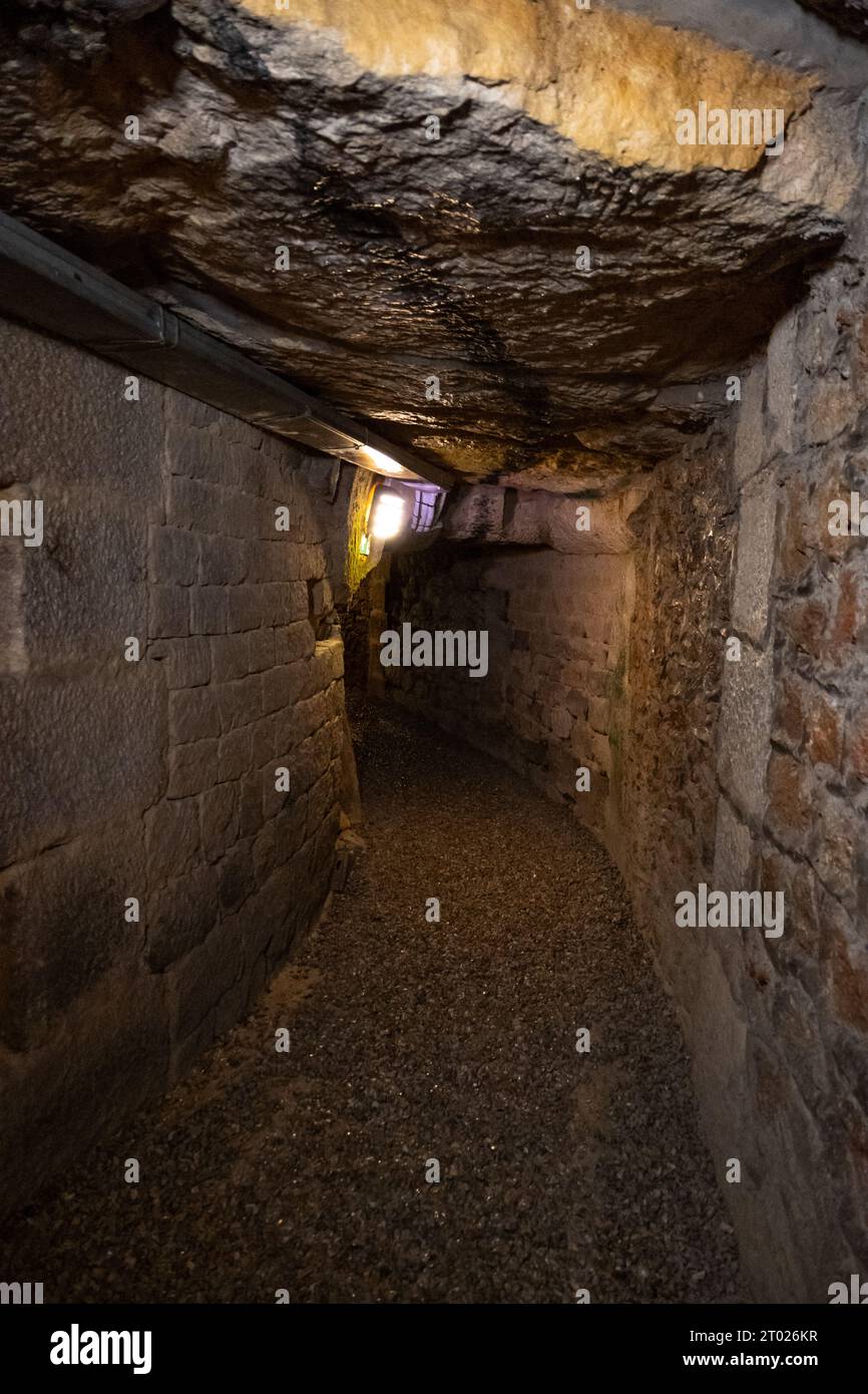 In the Paris Catacombs, a long underground path with structures formed ...