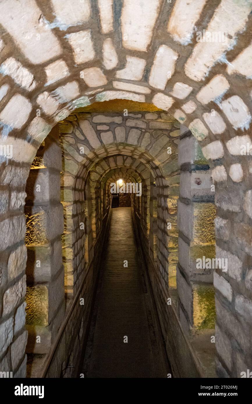 In the Paris Catacombs, a long underground path with structures formed ...
