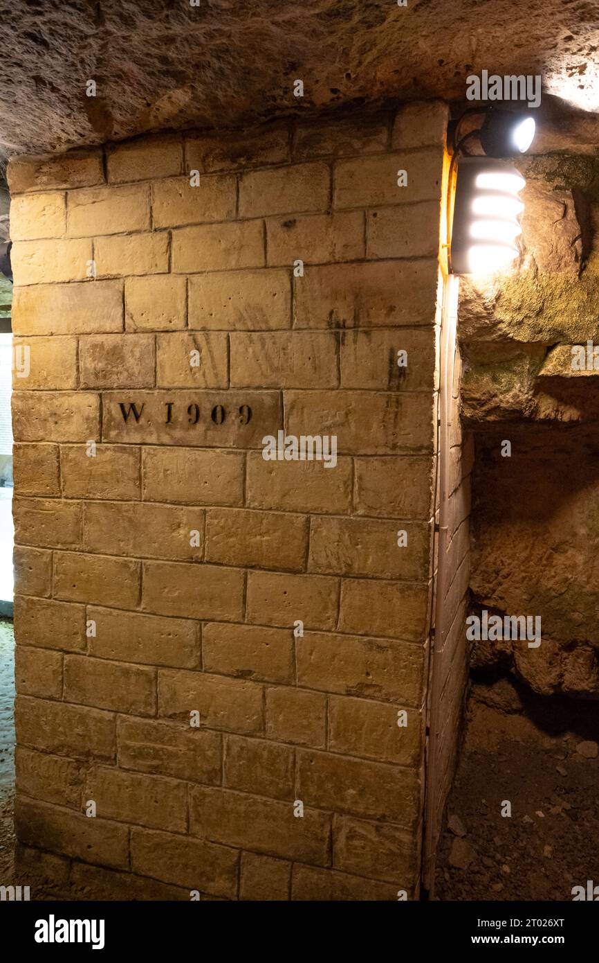 In the Paris Catacombs, a long underground path with structures formed ...