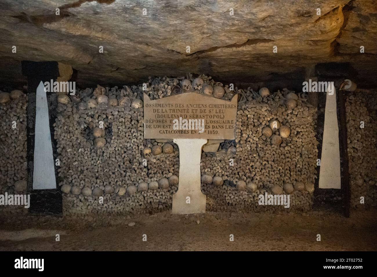 In the Paris Catacombs, a long underground path with structures formed ...