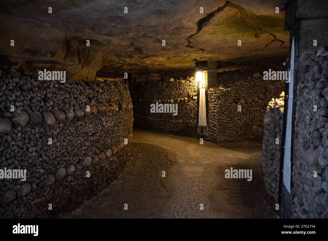 In the Paris Catacombs, a long underground path with structures formed ...